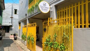 Um edifício com uma placa indicando 'Decasa House' e um portão amarelo.