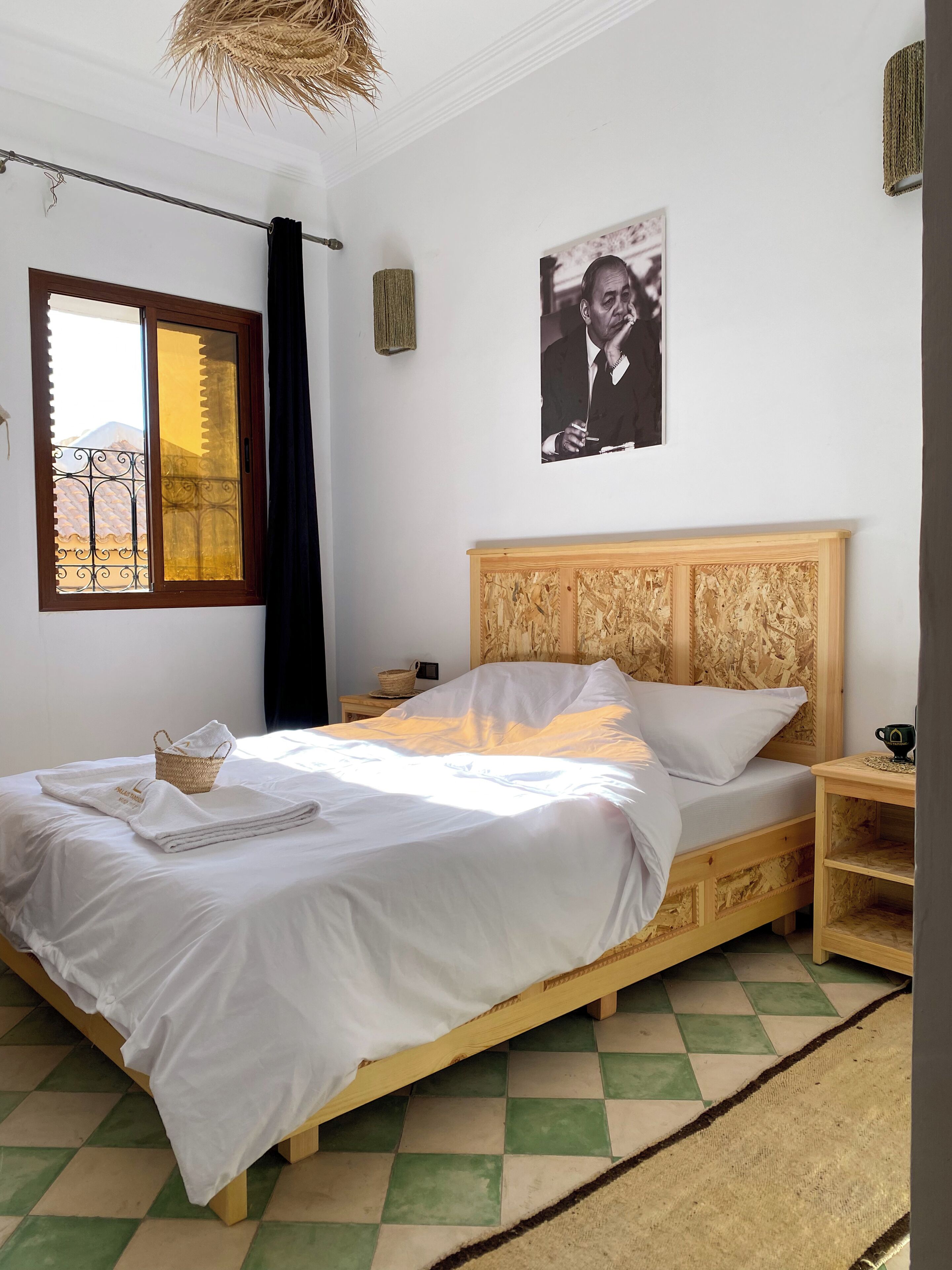 Quarto com uma cama, cabeceira de madeira, mesa de cabeceira, quadro na parede e janela com vista.