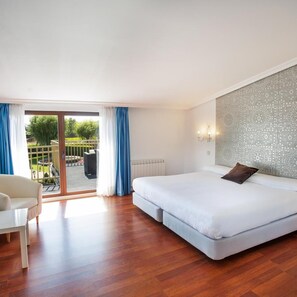 Quarto de hotel com uma cama grande, uma cadeira, vista para o exterior e parede estampada.