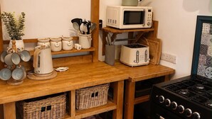 Uma cozinha com bancada de madeira, micro-ondas, torradeira e fogão.