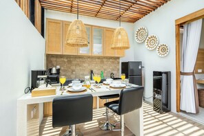 Uma cozinha moderna com área de jantar, apresentando backsplash de pedra, armários de madeira e luminárias pendentes.