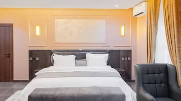 Quarto moderno com uma cama grande, uma cadeira e ar condicionado fixado na parede.