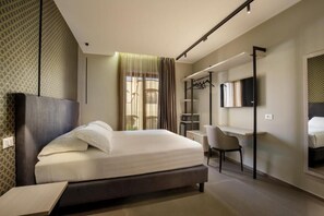 Quarto de hotel moderno com cama, escrivaninha, cadeira e televisão.