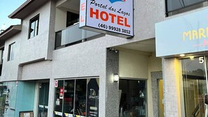 A hotel with a signboard advertising 'Portal dos Lagos HOTEL' and a contact number.