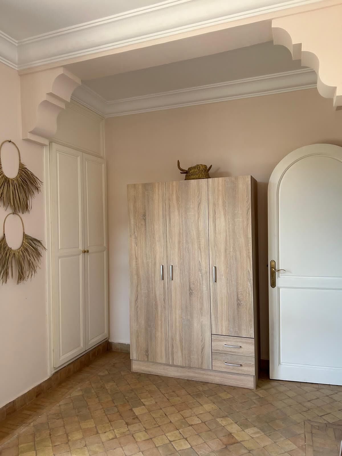 Quarto com guarda-roupa de madeira, porta branca e chão estampado.