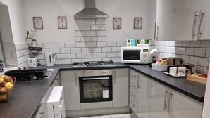 Uma cozinha moderna com armários cinzentos, forno embutido, micro-ondas e fogão a gás.