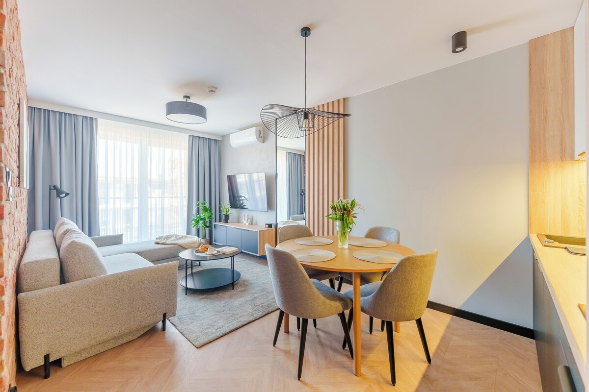 Uma sala de estar moderna com um sofá, mesa de jantar, cadeiras e uma televisão.