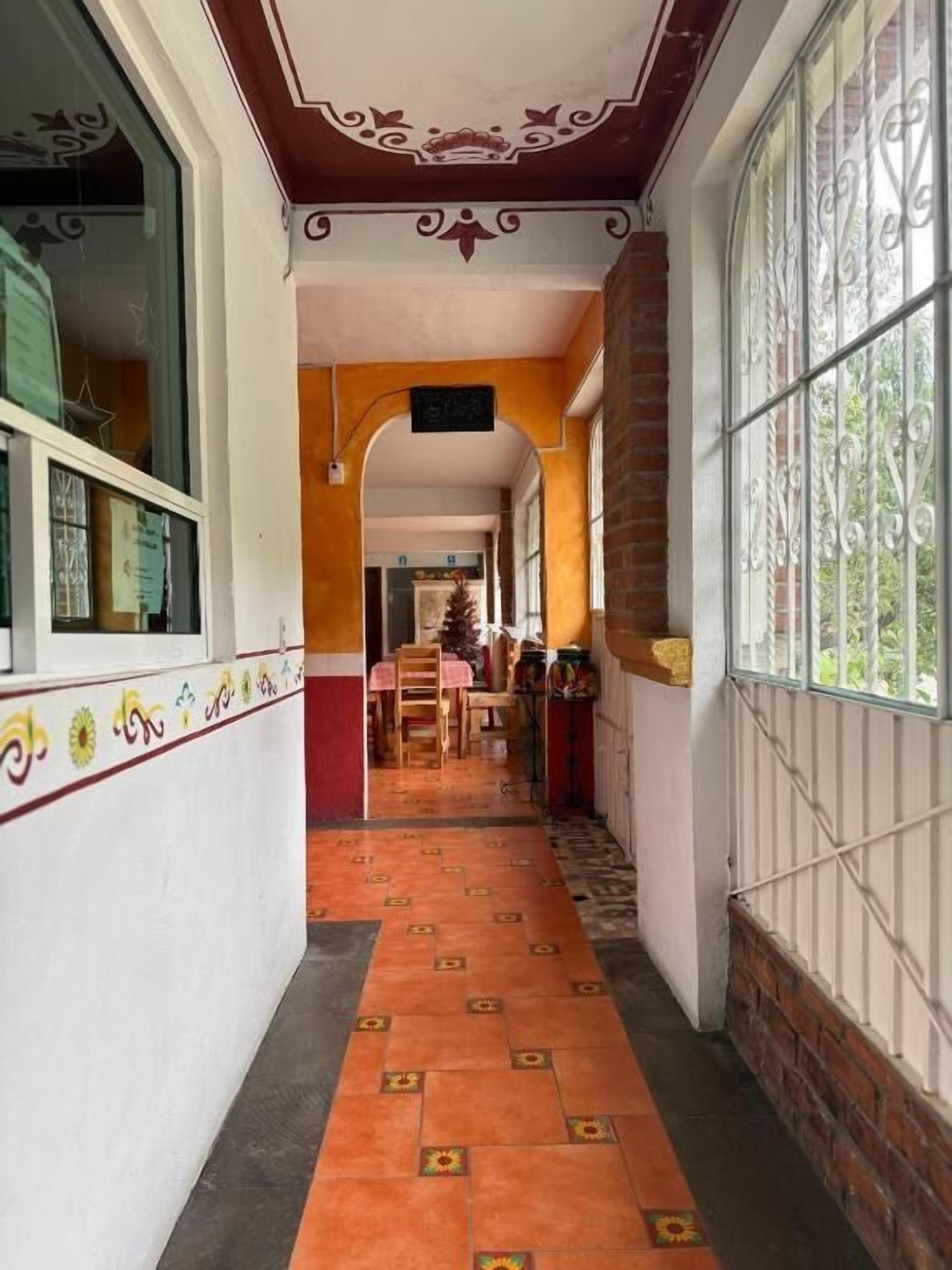 Um corredor com piso estampado, uma escada e uma sala de jantar com uma árvore de Natal.