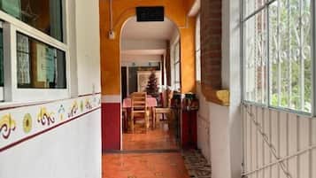 Um corredor com piso estampado, uma escada e uma sala de jantar com uma árvore de Natal.