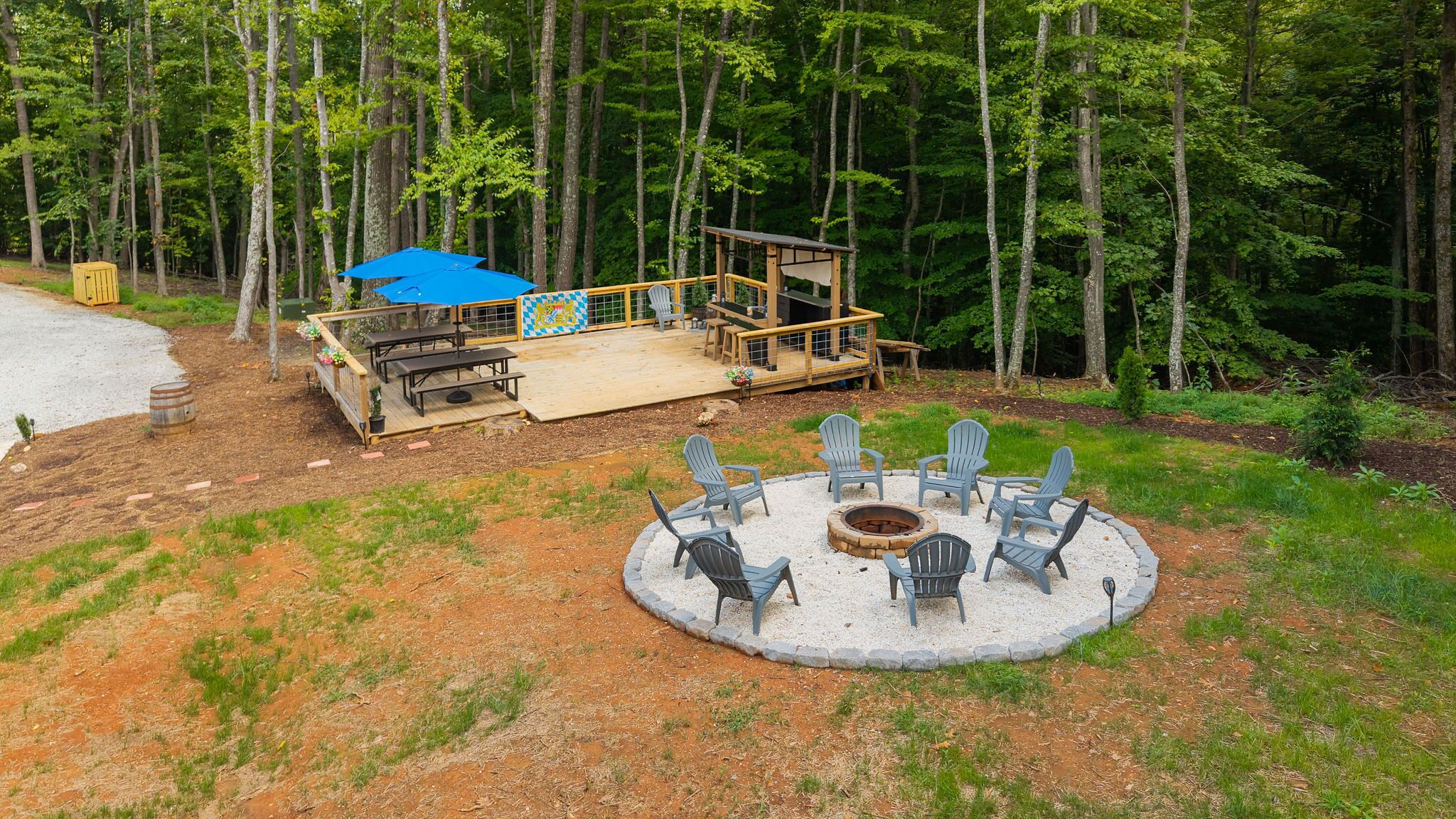 Um terraço com área de estar externa e uma lareira cercada por cadeiras Adirondack.