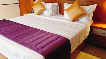 Quarto de hotel com uma cama grande, mesa de cabeceira e criado-mudo.