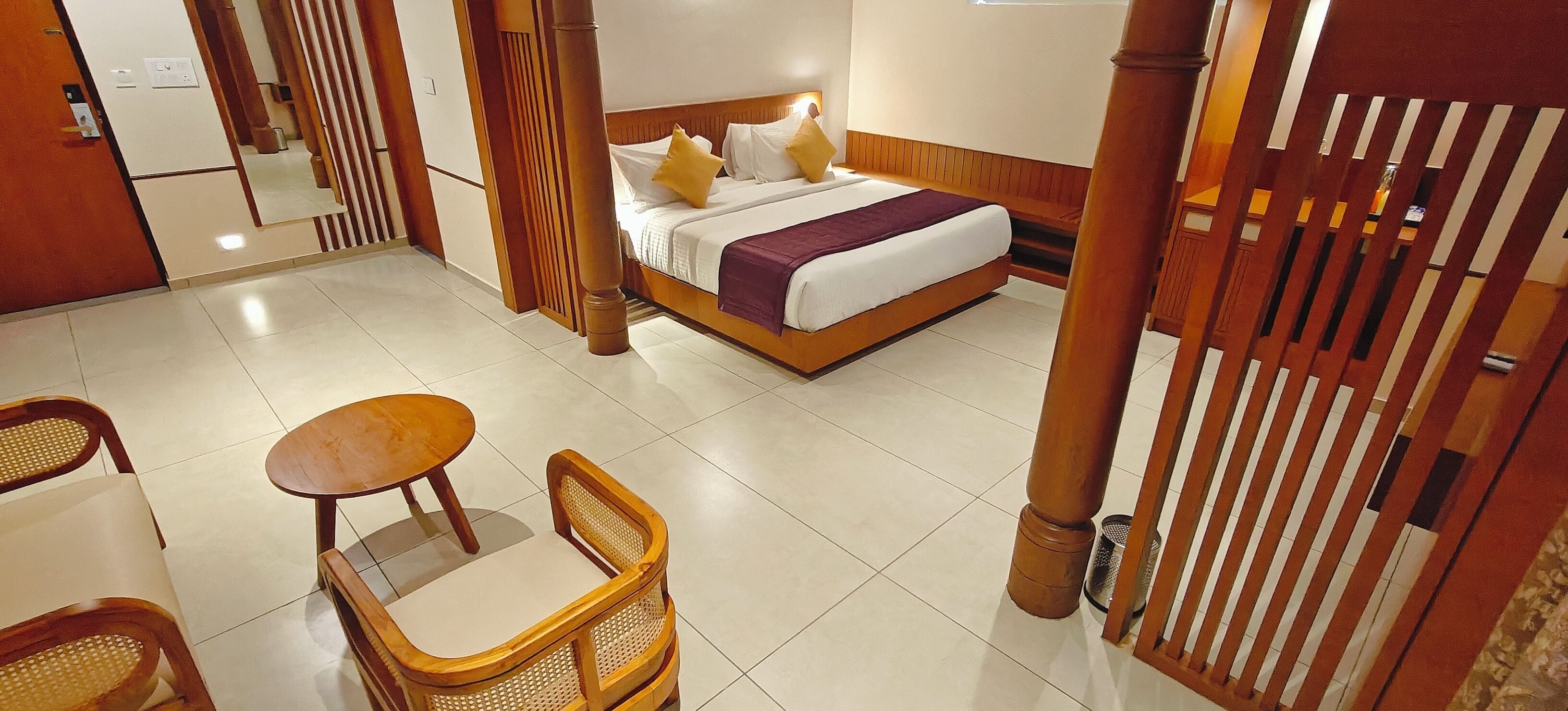 Quarto de hotel com uma cama, uma mesinha e duas cadeiras.