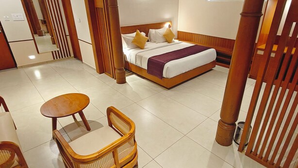 Quarto de hotel com uma cama, uma mesinha e duas cadeiras.