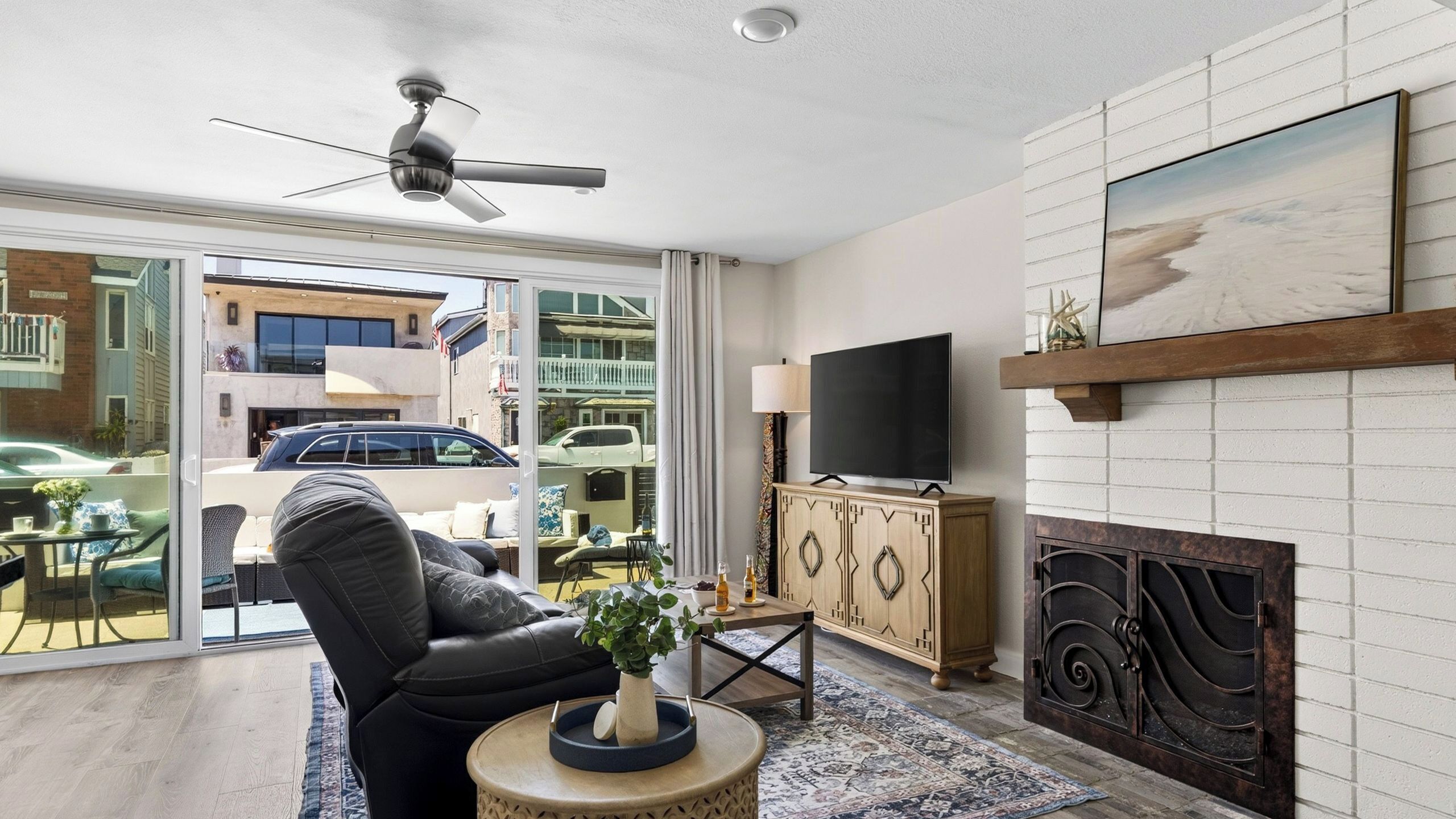 Uma sala de estar moderna com sofá de couro, televisão de tela plana, lareira e varanda com vista para a cidade.