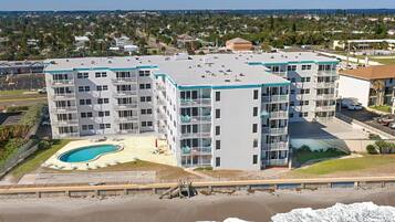 Um hotel com vários andares, piscina, acesso à praia e vista para o oceano.
