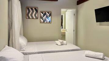 Quarto de hotel com duas camas, uma televisão de tela plana e duas obras de arte penduradas na parede.