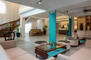 Ampla sala de estar com escada, sofás, mesa de centro e balcão de recepção.
