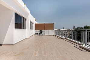 Terraço no telhado com churrasqueira, vista da cidade e guarda-corpo.