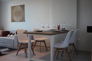 Uma zona de refeições moderna com uma mesa minimalista, cadeiras brancas e um objeto decorativo na parede.