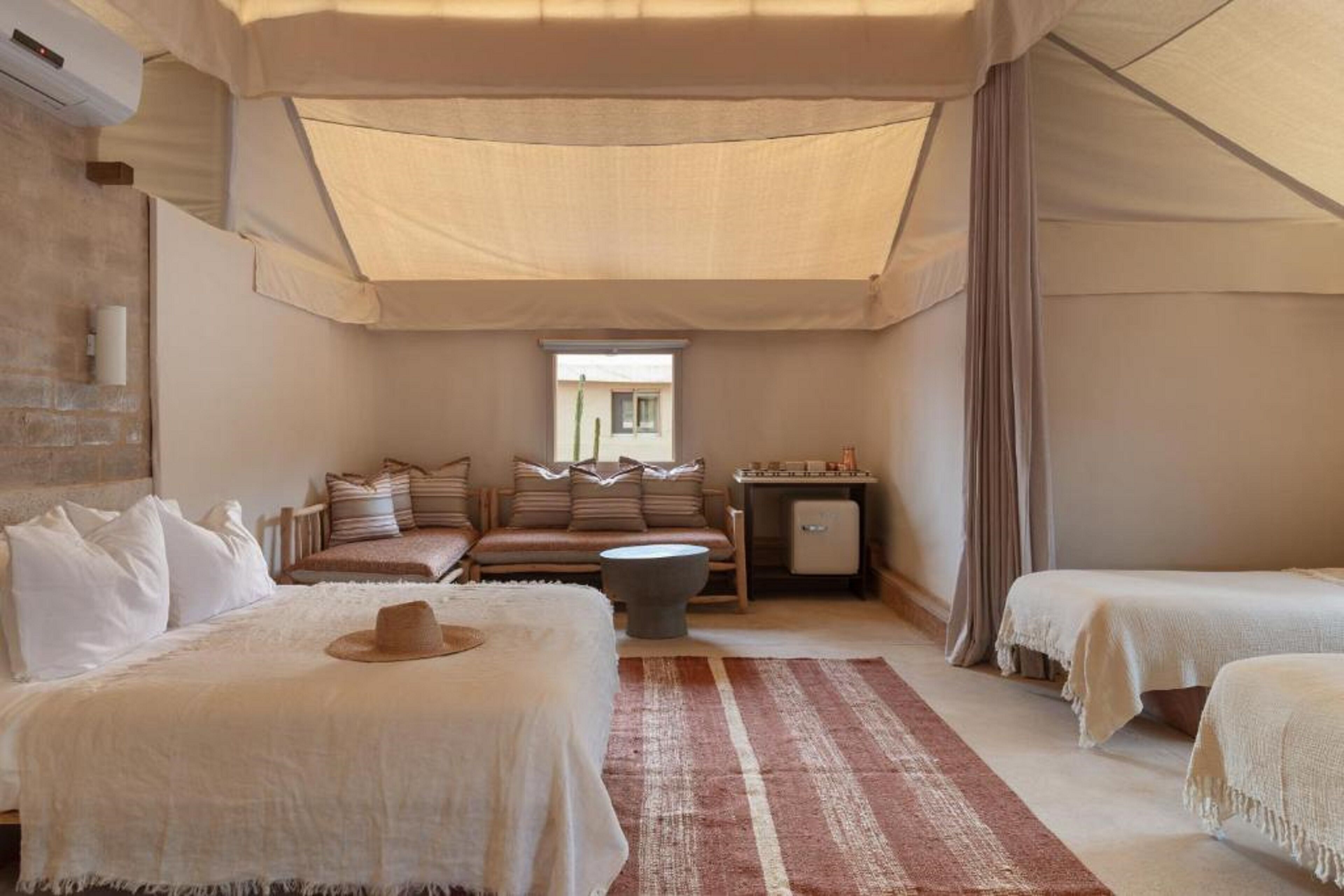 Quarto com uma cama, dois sofás, uma mesinha e uma janela.