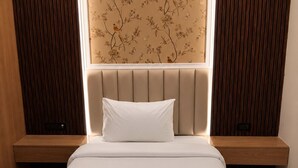 Quarto com uma cama, cabeceira, mesa de cabeceira e parede com padrão floral.