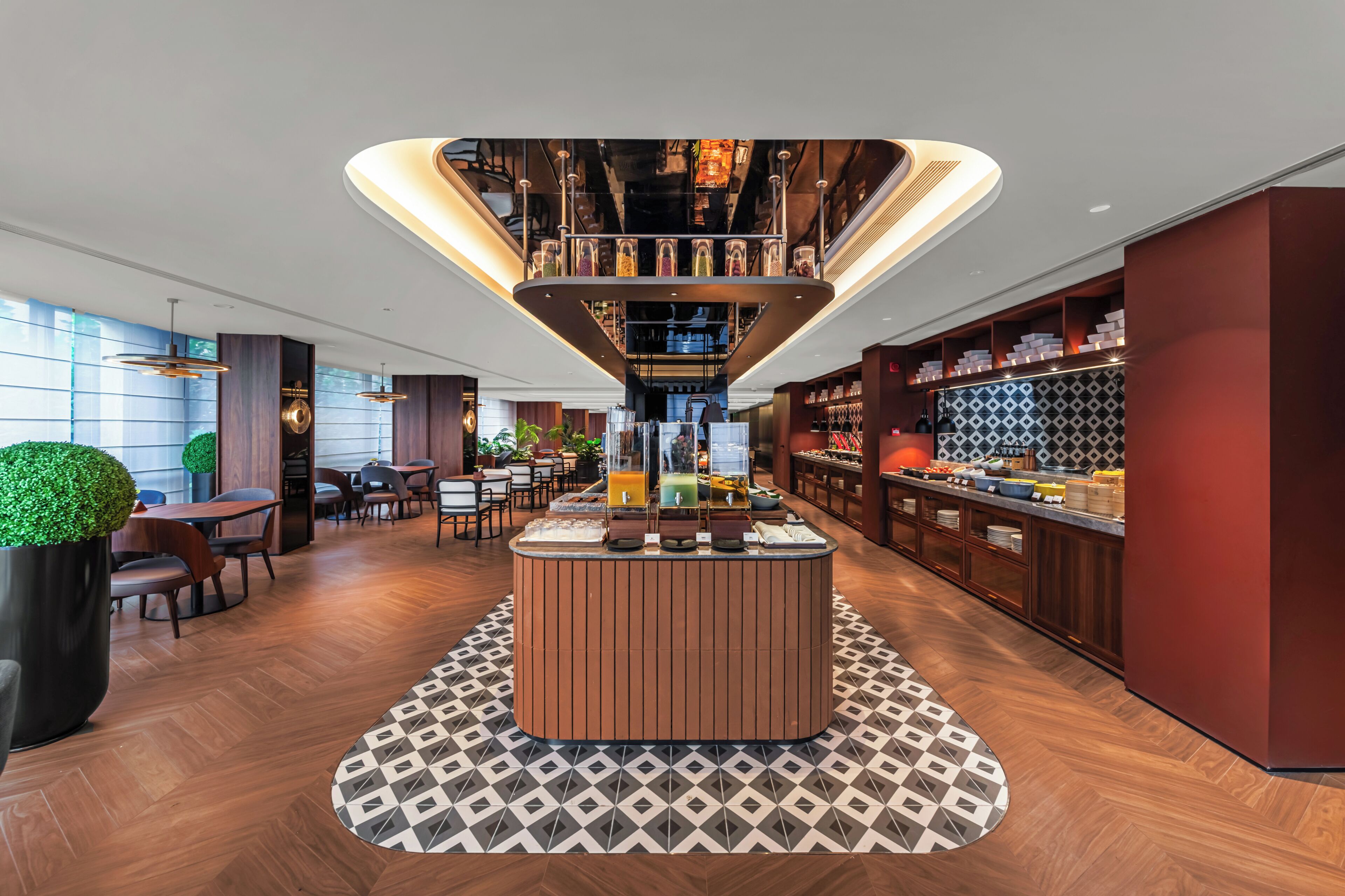 Um lobby de hotel moderno com um bar central, áreas de estar e piso estampado.