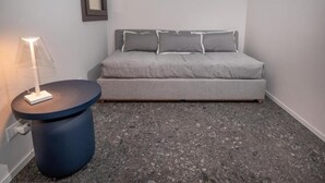 Quarto com uma cama, uma mesa redonda e um abajur.