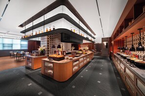 Interior moderno de restaurante com ilha central, pé direito alto e diversos tipos de assentos.