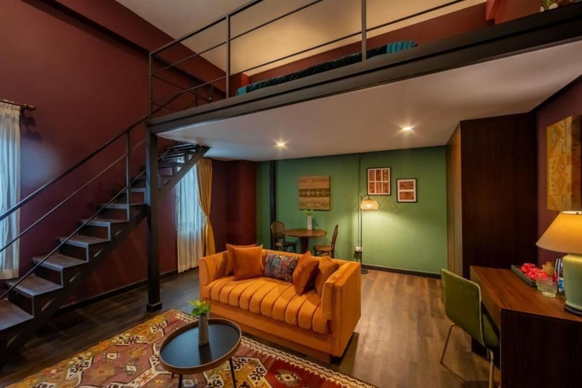 Uma sala de estar com sofá, mesa de centro, escada e área de jantar.