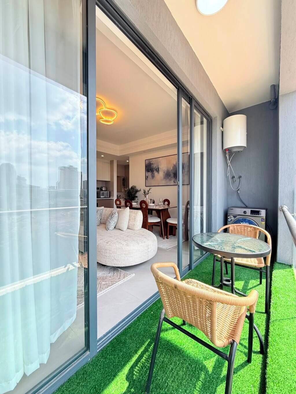 Um espaço moderno com sala de estar e uma porta de vidro que dá para uma área de jantar, mesa redonda com cadeiras e um aquecedor de água fixado na parede.