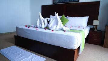 Quarto de hotel com uma cama, mesa de cabeceira, abajur e um quadro na parede.