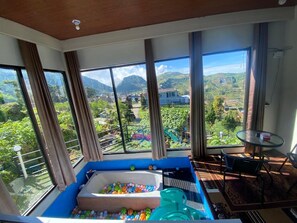 Um quarto com grandes janelas, uma banheira azul, uma mesinha e uma cadeira.