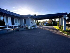 Um motel de dois andares com área de estacionamento coberta e céu claro.