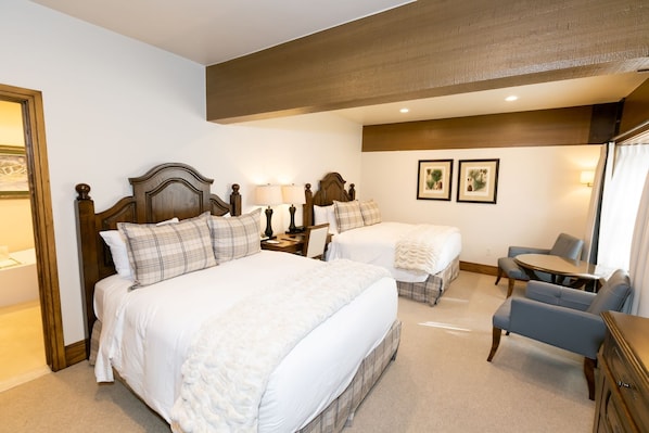 Quarto de hotel com duas camas, uma escrivaninha e uma cadeira.