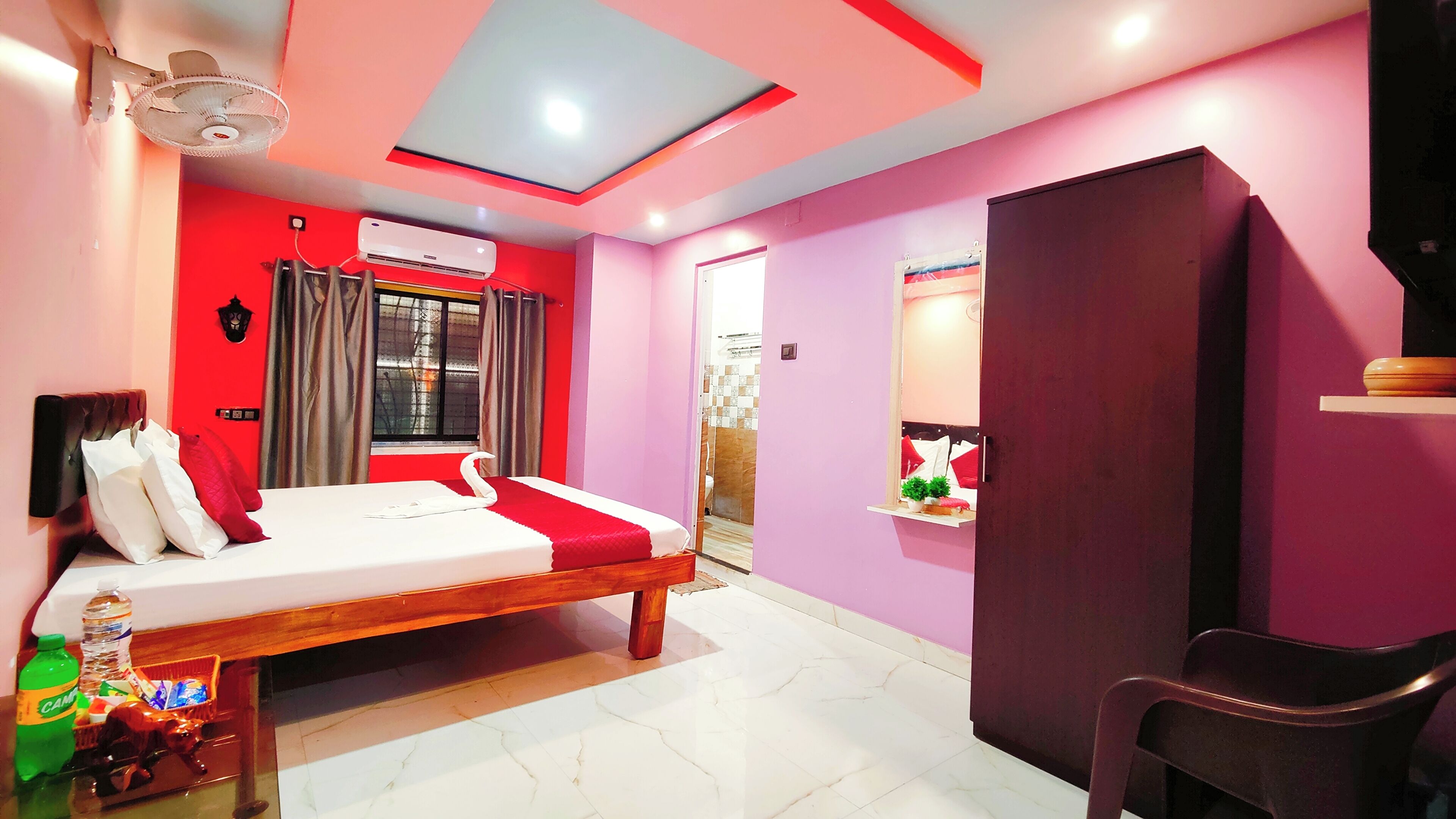 Quarto de hotel com cama, escrivaninha, cadeira, janela e ar condicionado.