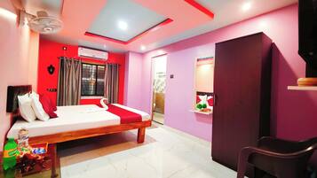 Quarto de hotel com cama, escrivaninha, cadeira, janela e ar condicionado.