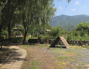 Um parque com um caminho pavimentado, uma estrutura inclinada e uma montanha ao fundo.