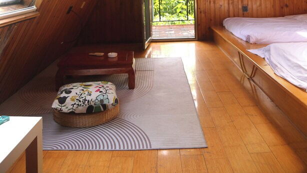 Um quarto com teto inclinado, uma cama, uma janela e uma porta que dá para o exterior.