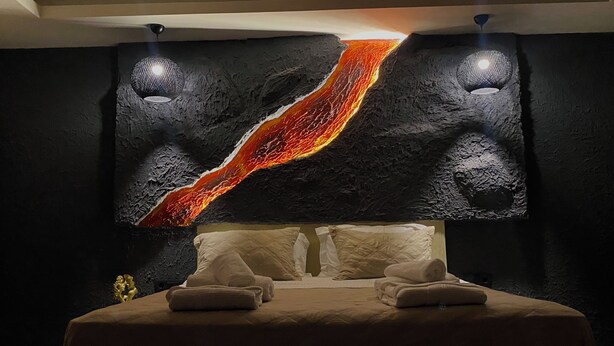 Quarto com cama, almofadas e um mural na parede.