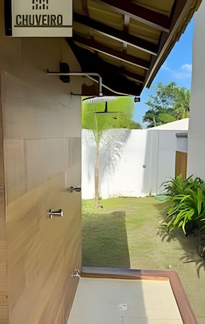Uma entrada para uma área externa coberta, com uma placa que diz 'CHUVEIRO'.