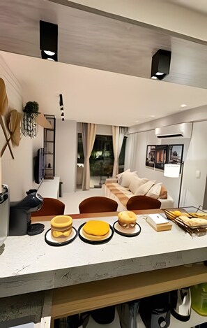 Uma sala de estar moderna com um sofá, uma mesa de jantar com pratos e vista para o exterior.