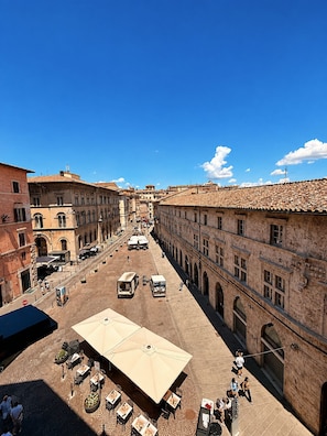 Uma praça ampla com área central aberta, rodeada por edifícios históricos com janelas em arco e telhados em azulejo.