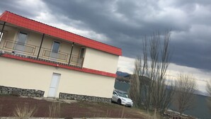Um edifício com telhado vermelho, varanda e alicerce de parede de pedra.
