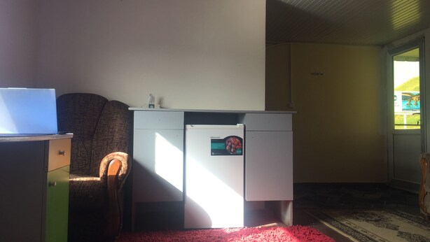 A room with a desk, chair, and a small refrigerator.