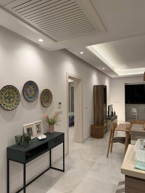 Uma sala de estar moderna com área de jantar, um aparador com pratos decorativos, um armário de madeira grande e uma televisão.