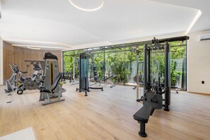 Uma academia moderna com diversos equipamentos de exercícios, grandes janelas e piso de madeira.