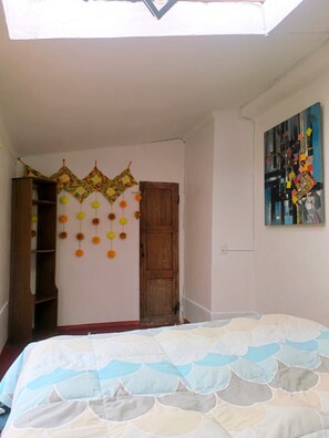 Quarto com cama, guarda-roupa, porta e uma obra de arte na parede.