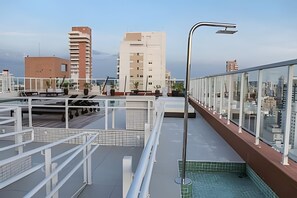 Terraço no telhado com piscina, grades e um candeeiro.