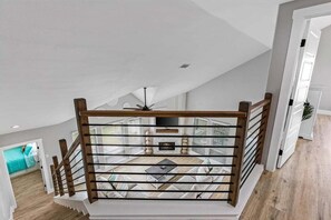Um quarto com pé-direito alto, escada de madeira, lareira e vista para outro cômodo.