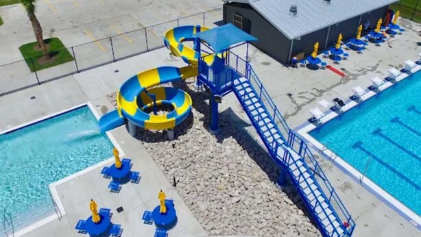 Uma área de piscina com escorregador, espreguiçadeiras e um espaço de estar coberto.